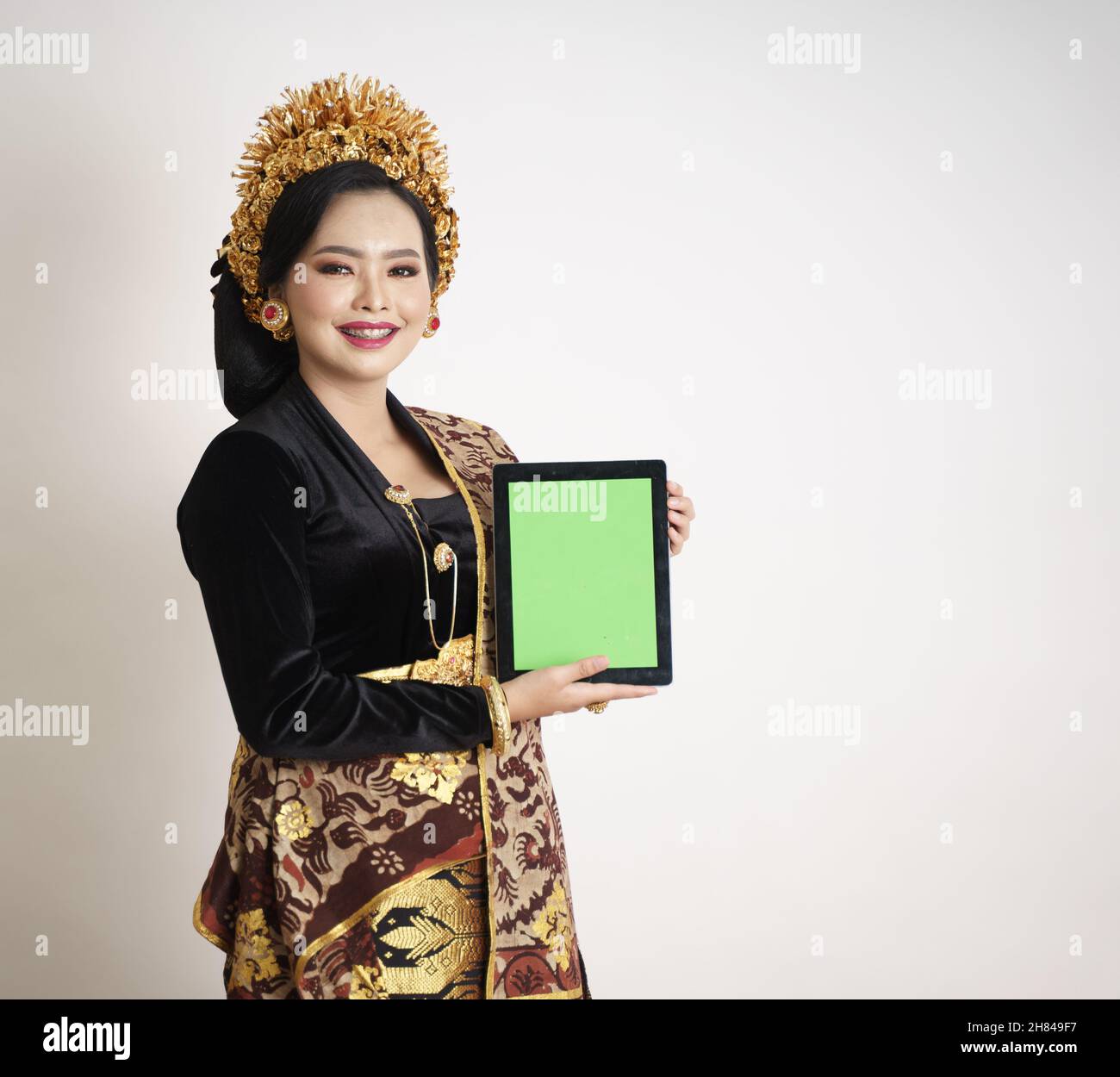 Smiling balinese woman wearing traditional clothes showing digital ...