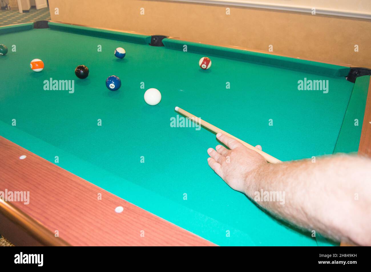 A close-up of a billiard table with balls pointing the athlete's hands ...