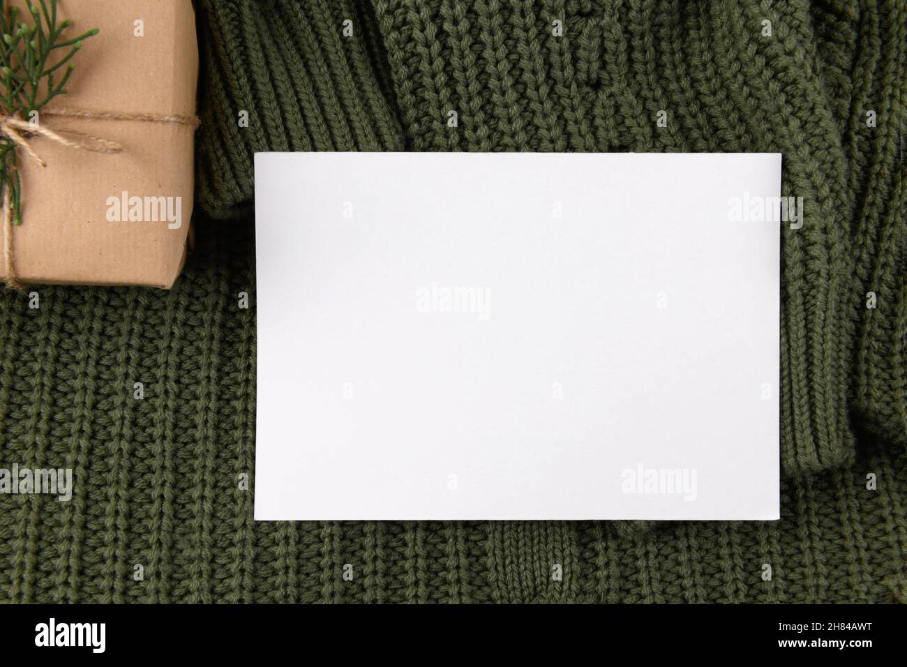 Blank 7x5 card mockup kraft gift box with fir decoration on knitted ...