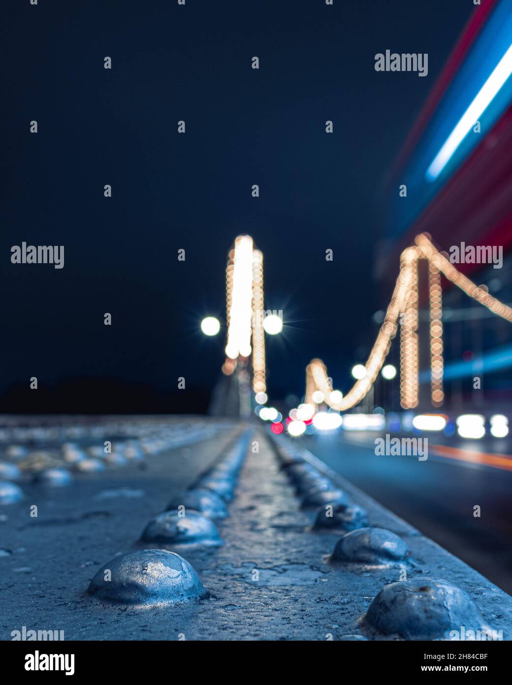 A bus speeding across Chelsea Bridge at night leaving dramatic light ...