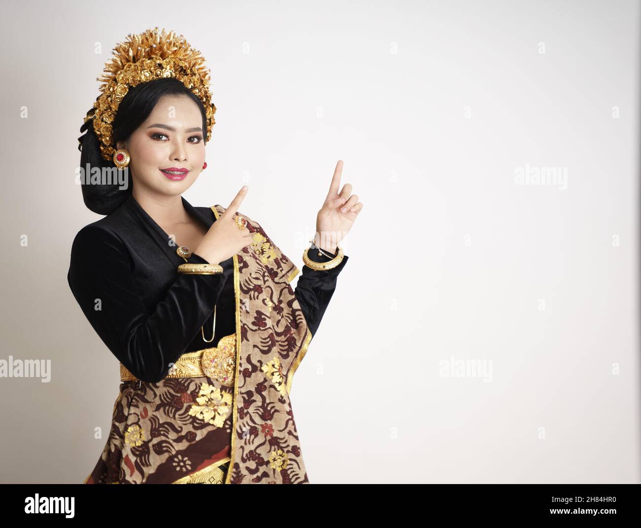 Smiling balinese woman wearing traditional clothes with finger pointing ...