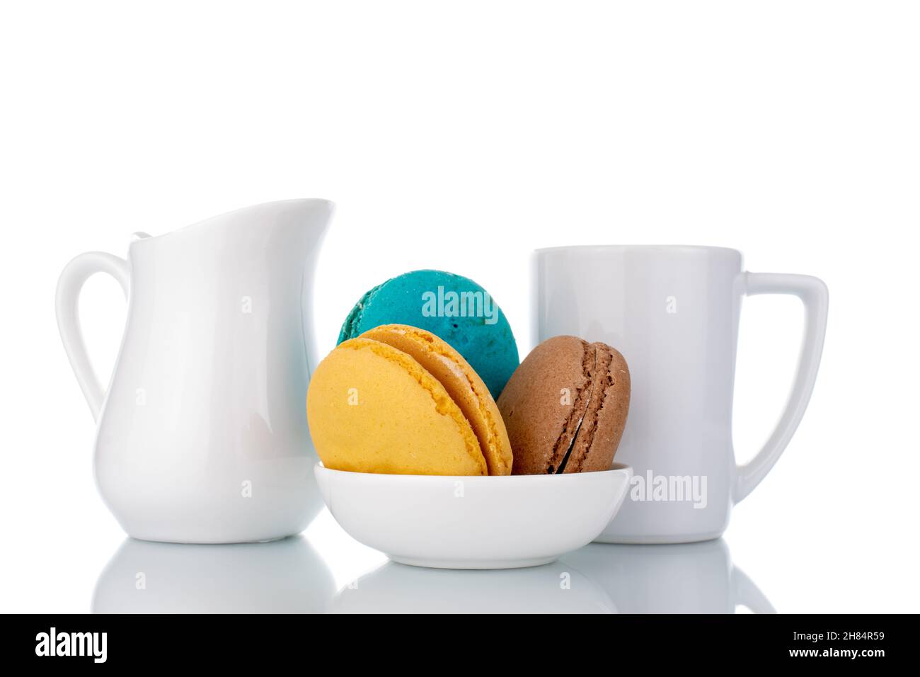 Three sweet macaroons with white ceramic dishes, close-up, isolated on ...