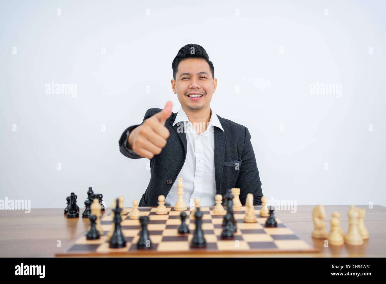 Man's thumbs up in suit playing chess Stock Photo - Alamy
