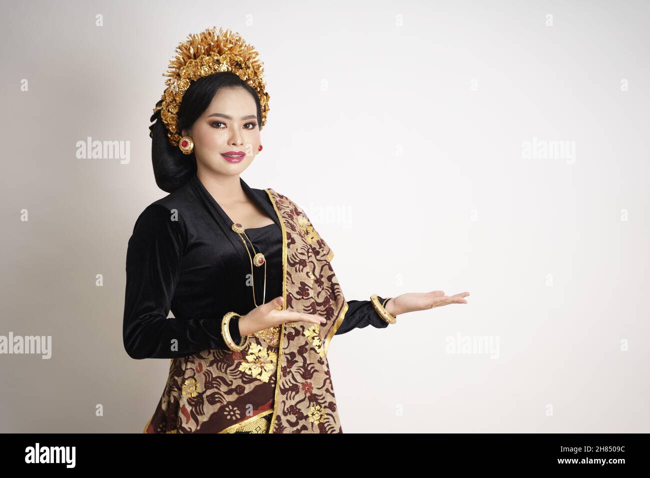 Smiling balinese woman wearing traditional clothes with hand gestures ...