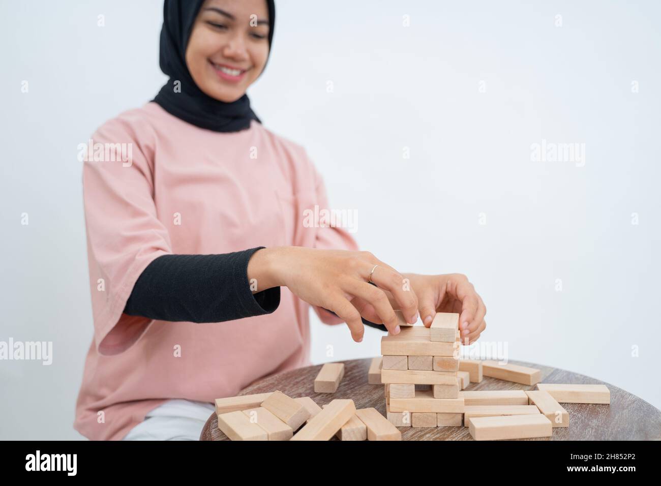 Woman in veil arranging blocks while playing wooden block tower Stock ...