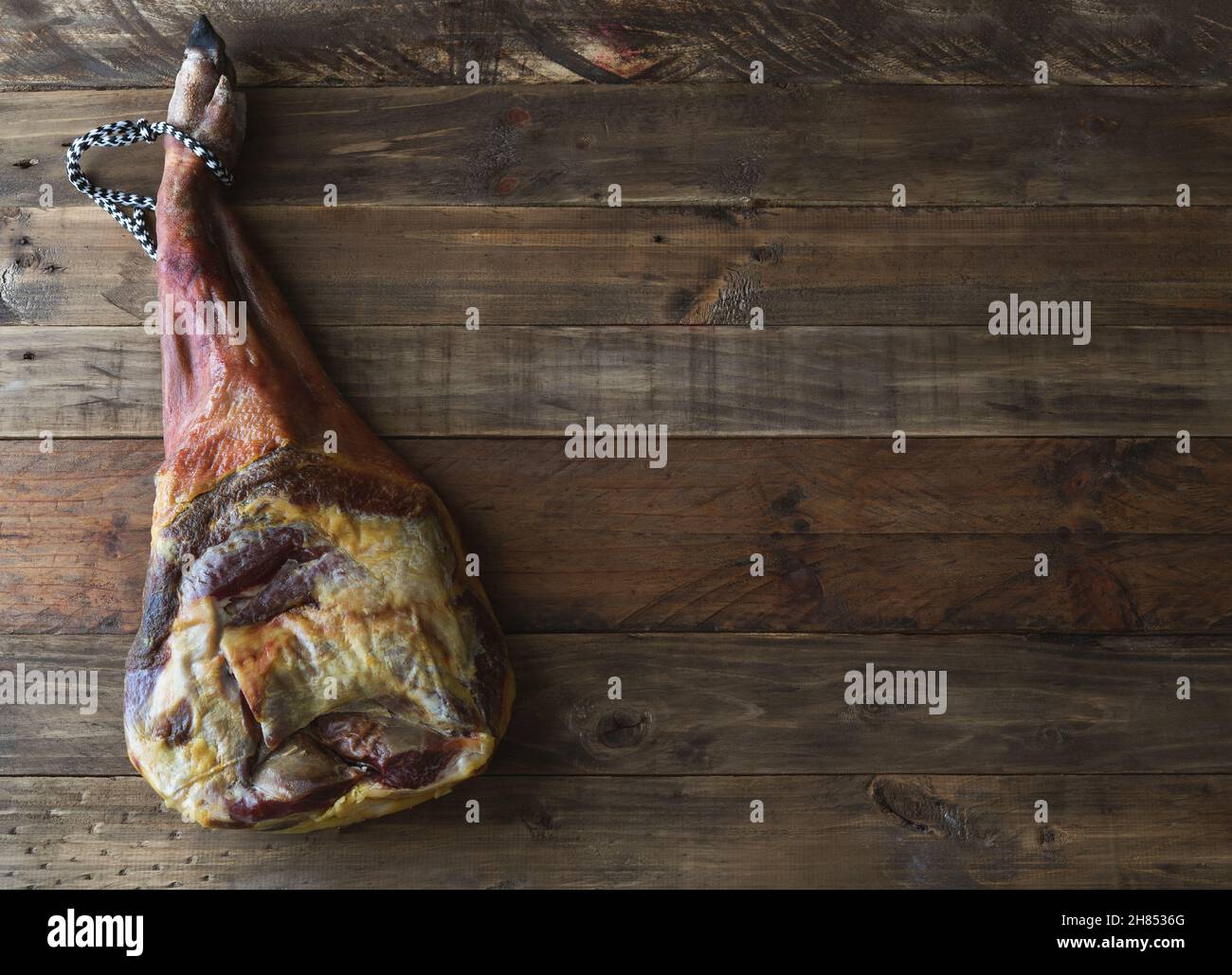 Cured pork shoulder on a rustic wooden base. Copy space. Cured pork leg ...