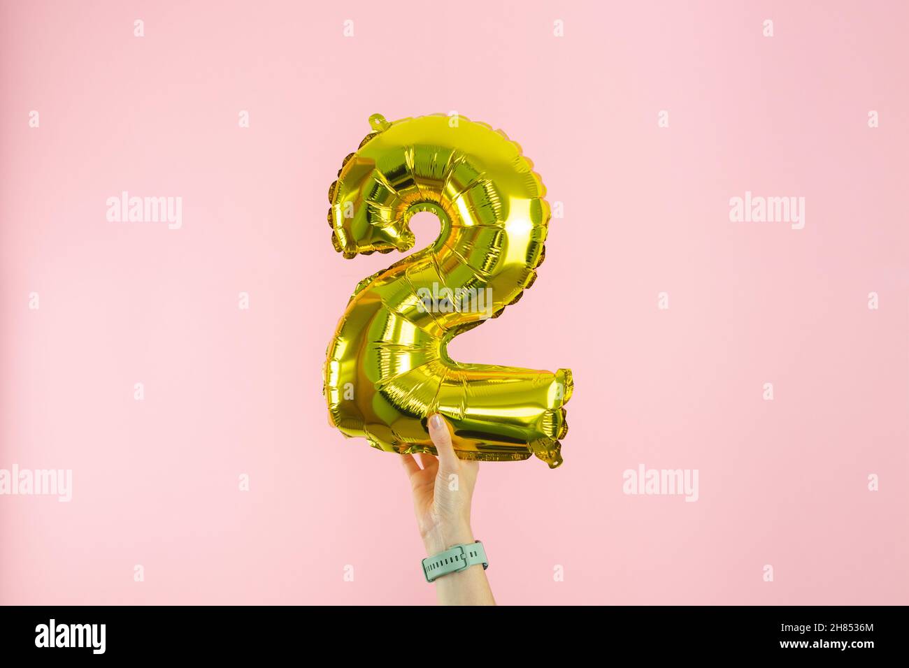 Woman's hand with watch holding golden globe in the shape of number 2 ...