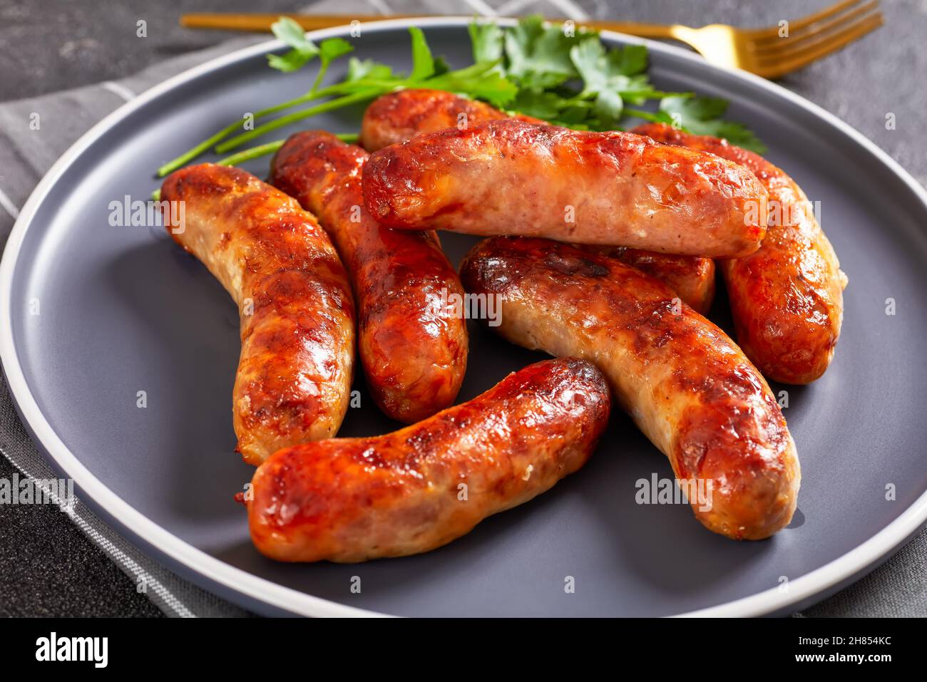 fried juicy bangers on a plate on a concrete table, top view, close-up ...