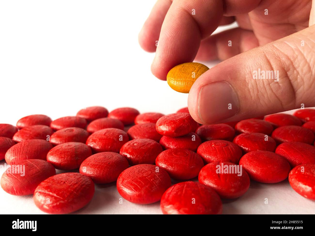 fingers holding a different colored object. red small wooden balls ...