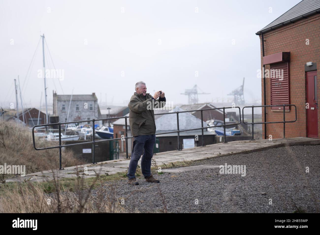 Redcar, UK. 27th Nov, 2021. A man takes a photo as huge waves crash ...