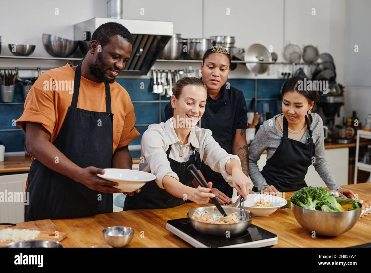 Diverse group of people cooking together during workshop in ...