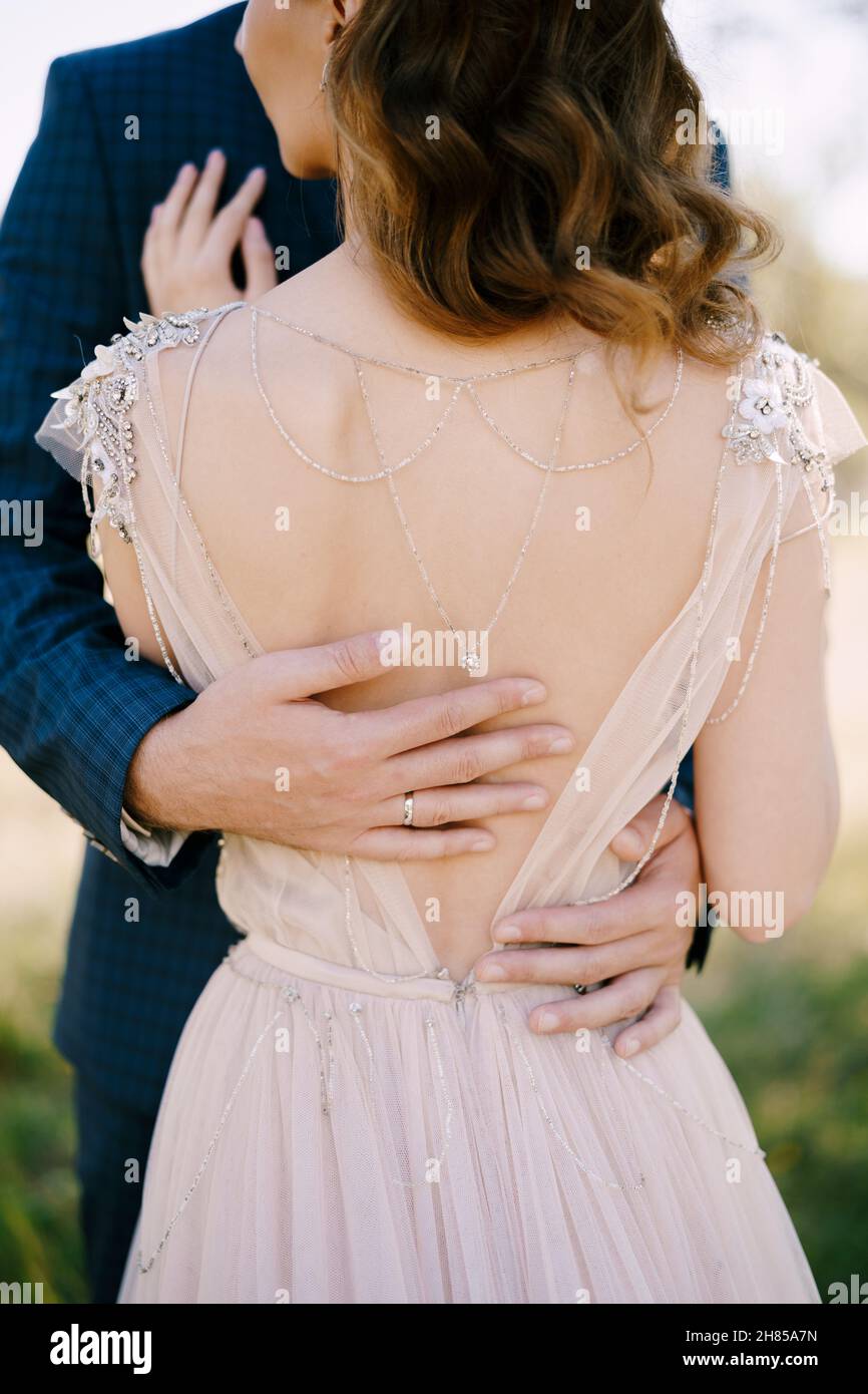 Groom hands hug bride lower back. Back view. Close-up Stock Photo - Alamy