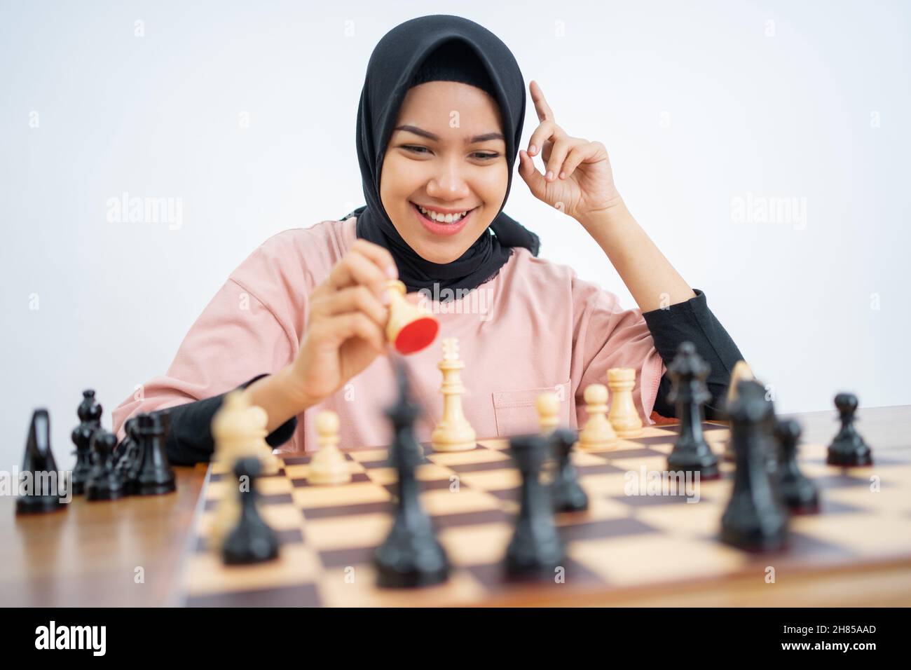 Smiling muslim woman hands holding chess pieces while playing chess ...