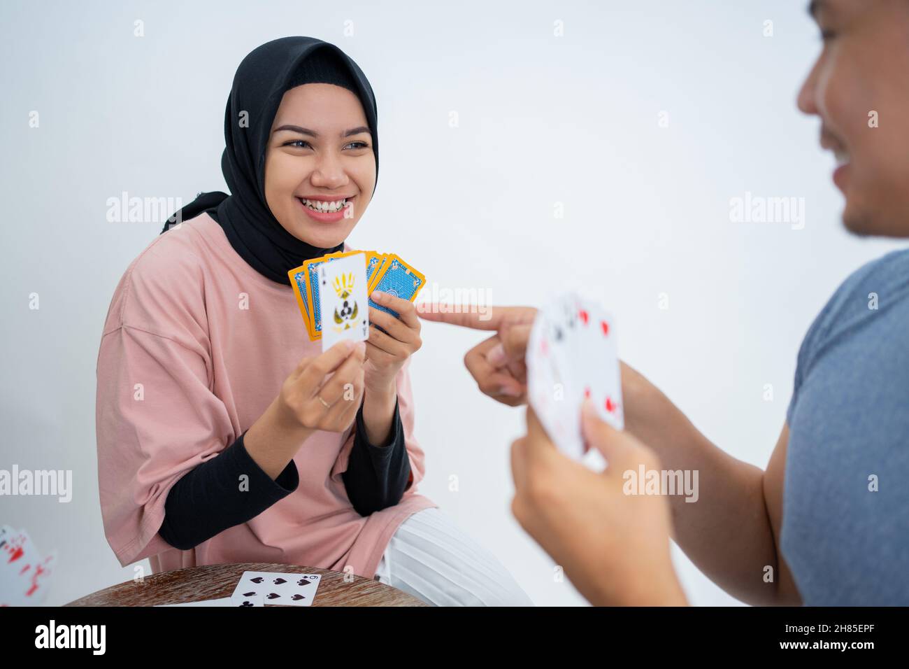 Woman showing one card while playing cards with male friends Stock ...