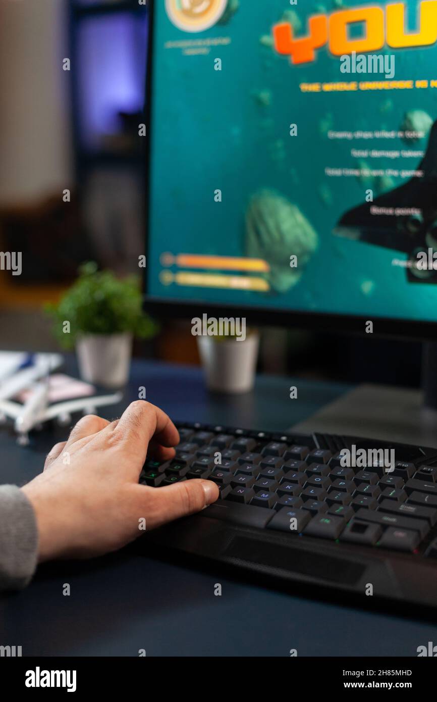 Close up of person using keyboard and playing video games on computer ...