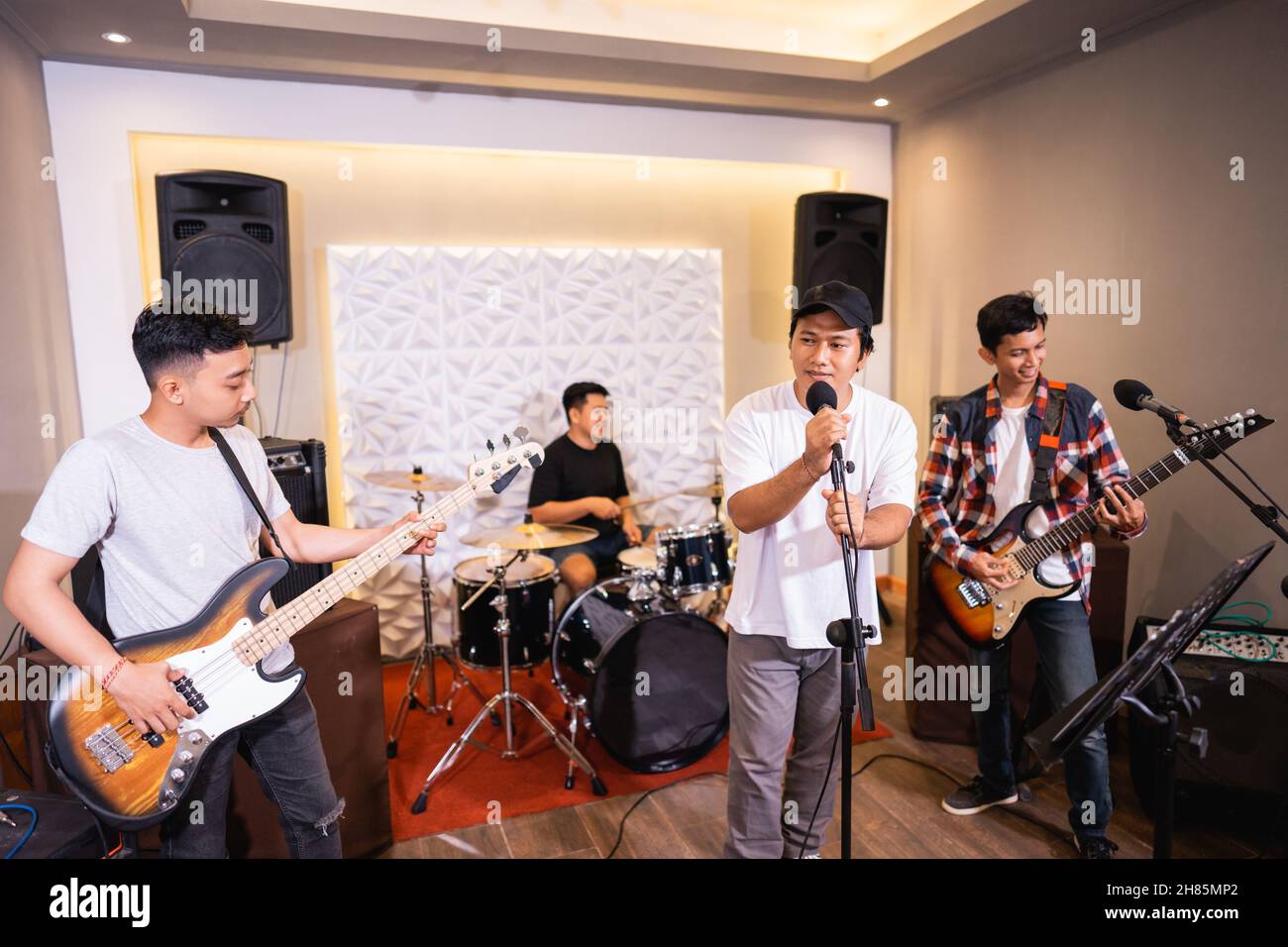 four young men as a band sing songs and play musical instruments during ...