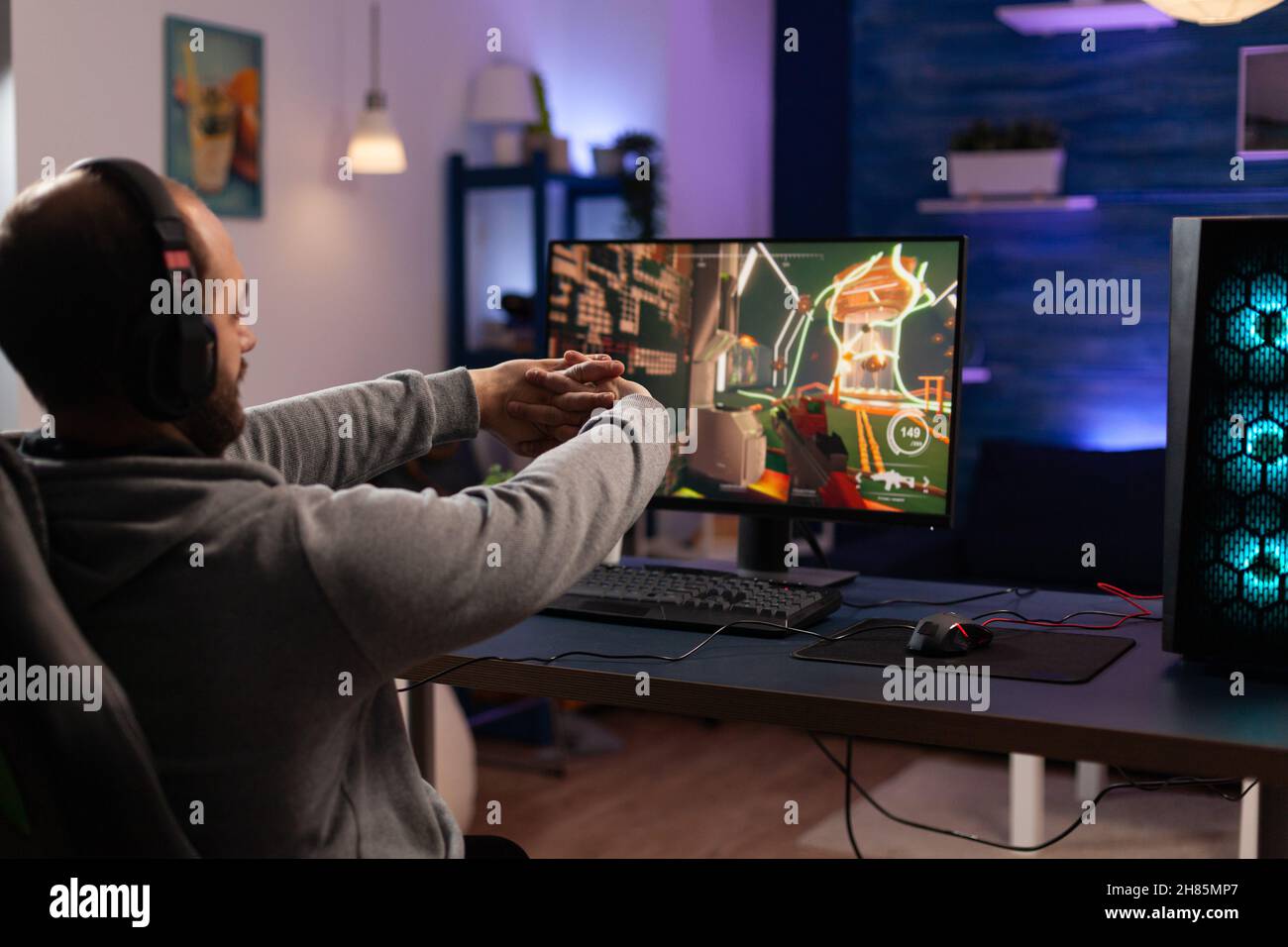 Gamer stretching before playing video games on monitor. Player with ...