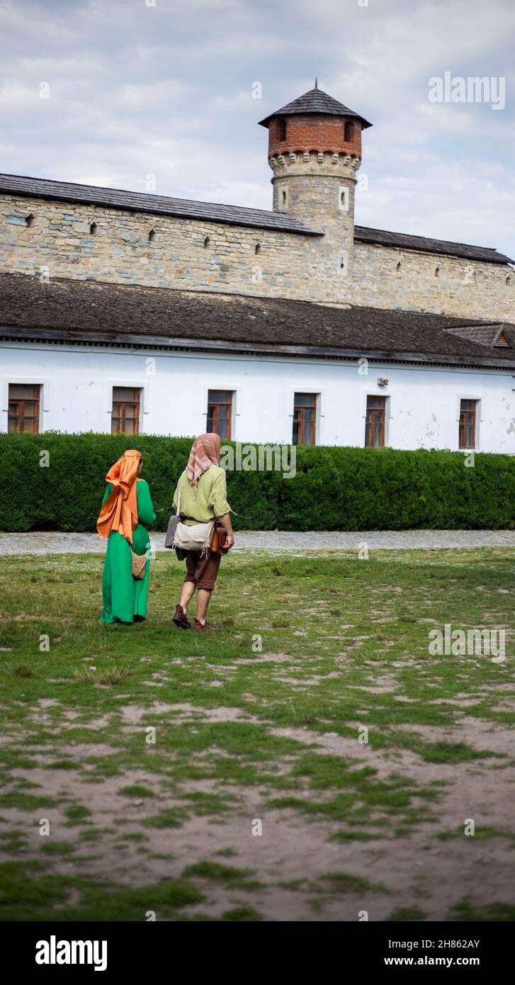 A guy and a girl in medieval clothes on the territory of the castle ...