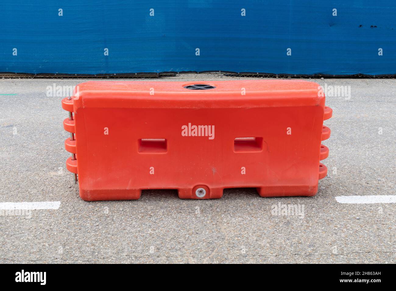 Bright orange plastic traffic barricade barrier on an asphalt road ...