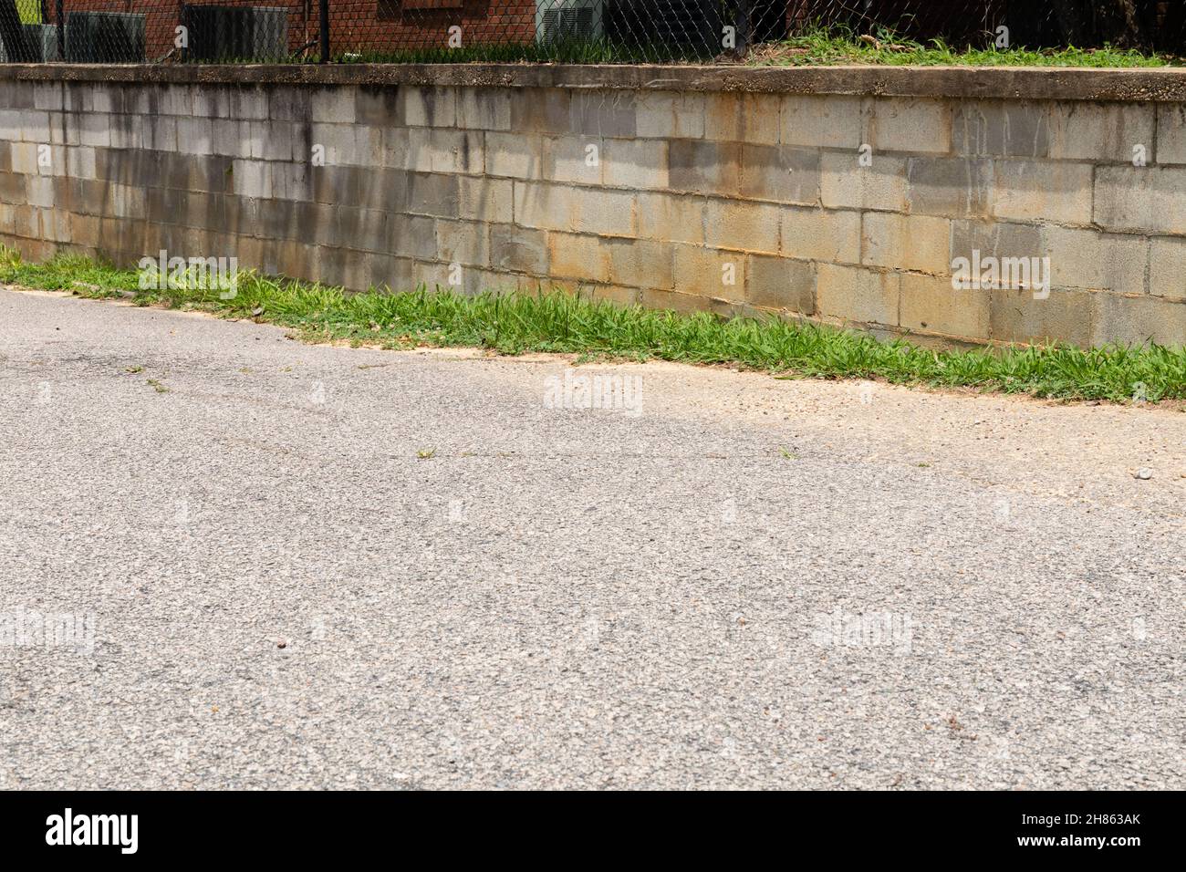 Concrete block retaining wall alongside an asphalt driveway, topped ...