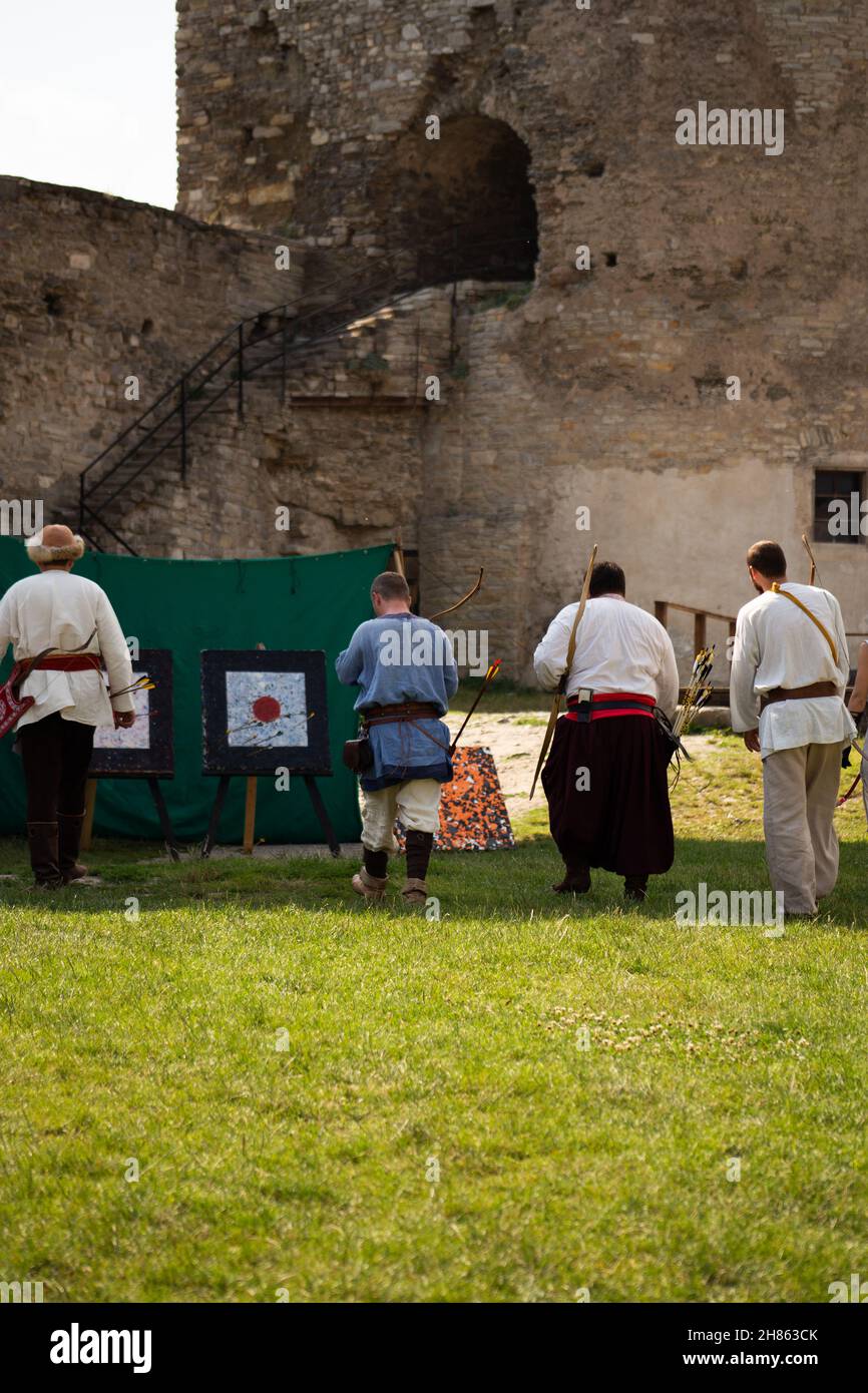 People in medieval clothes with bows on the territory of the castle ...
