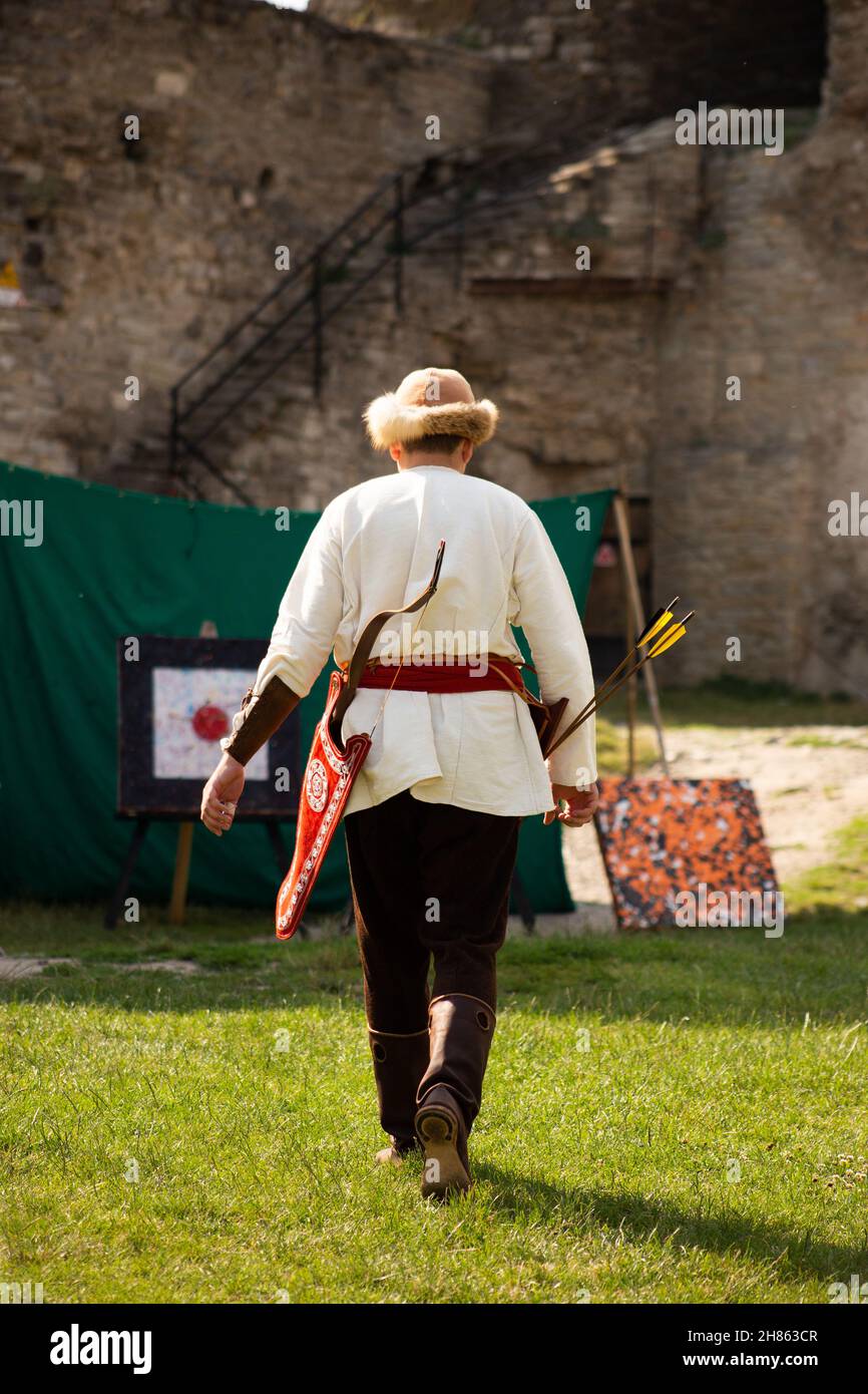 People in medieval clothes with bows on the territory of the castle ...