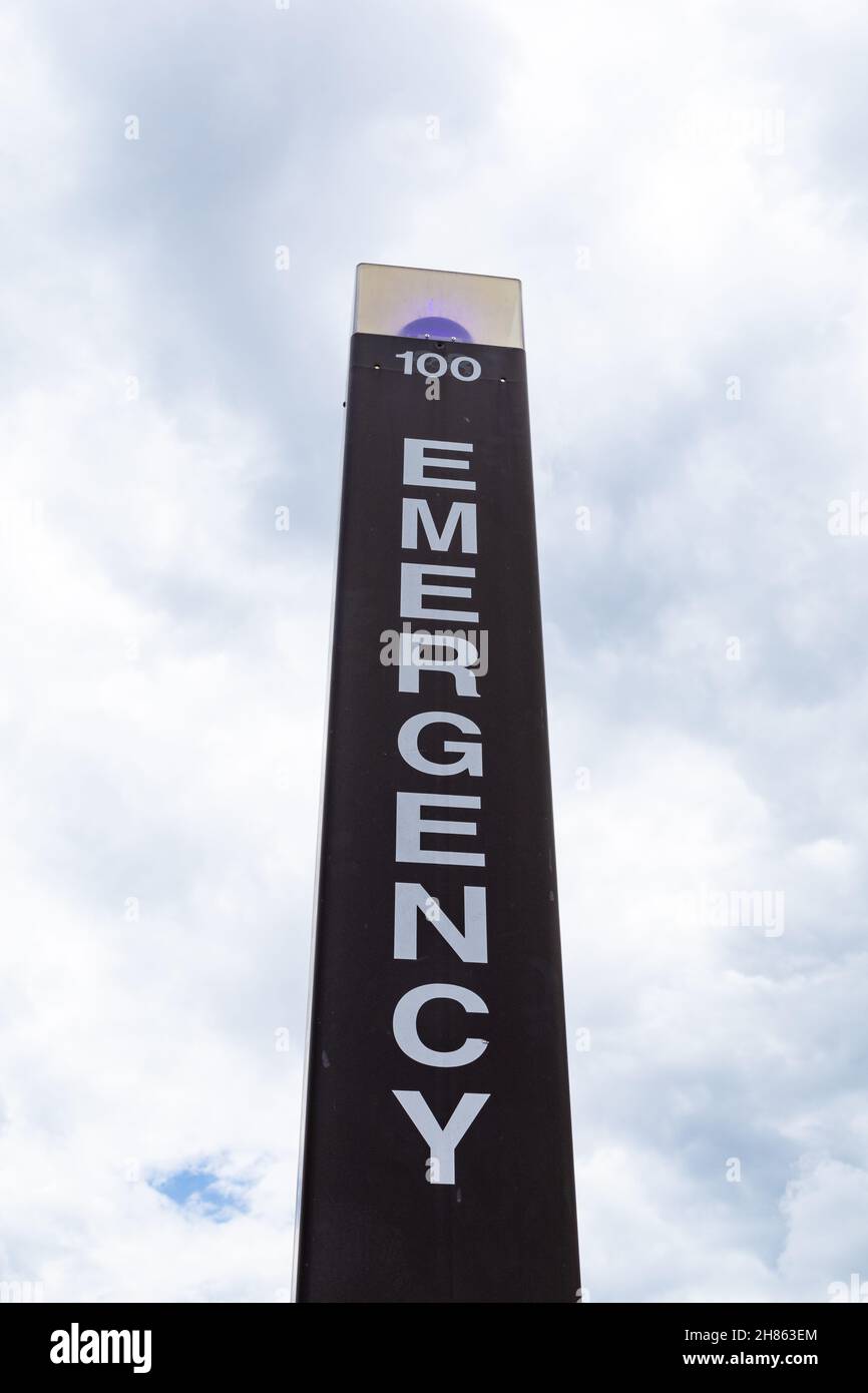 View looking up at a blue light emergency call box against a cloudy sky ...