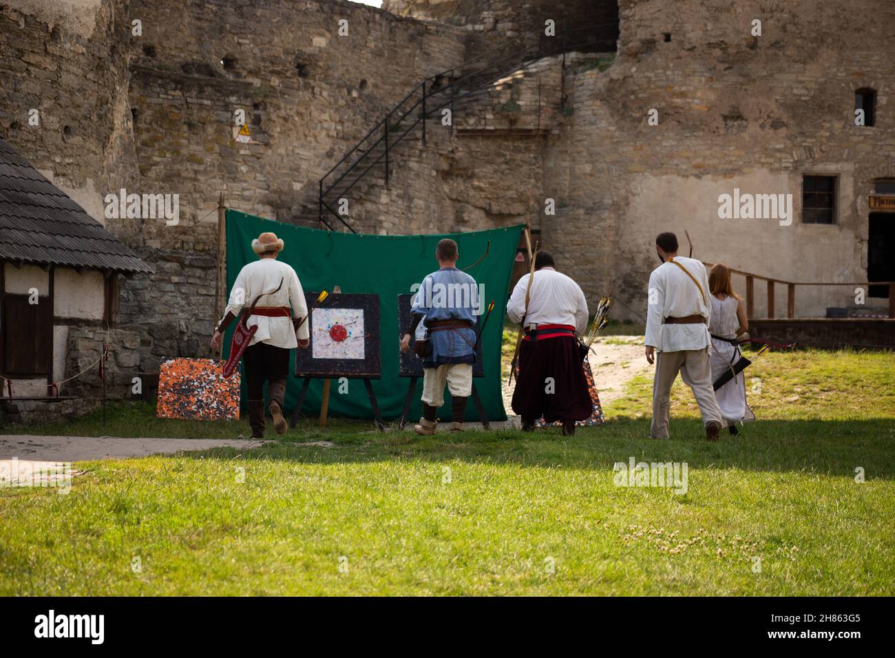 People in medieval clothes with bows on the territory of the castle ...