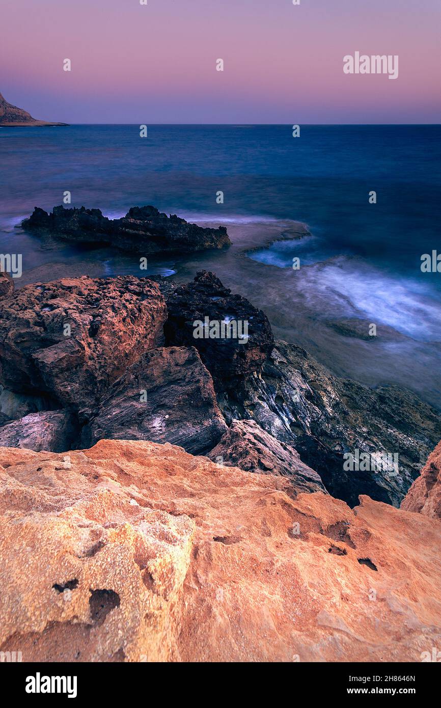 A vertical shot of rocks in the sea at the beautiful sunset in Cyprus ...