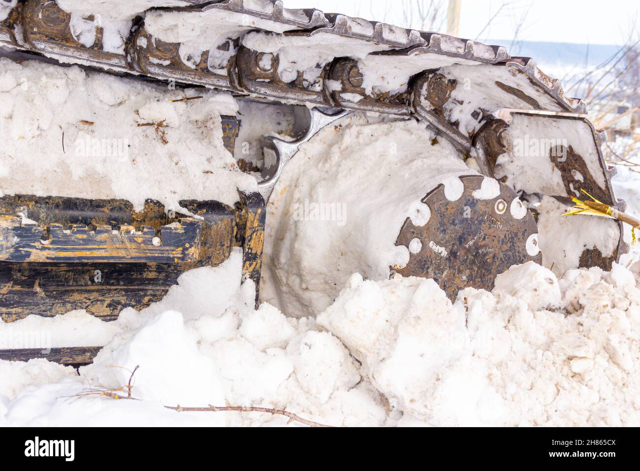 the drive gear of a crawler excavator is covered with compressed snow ...