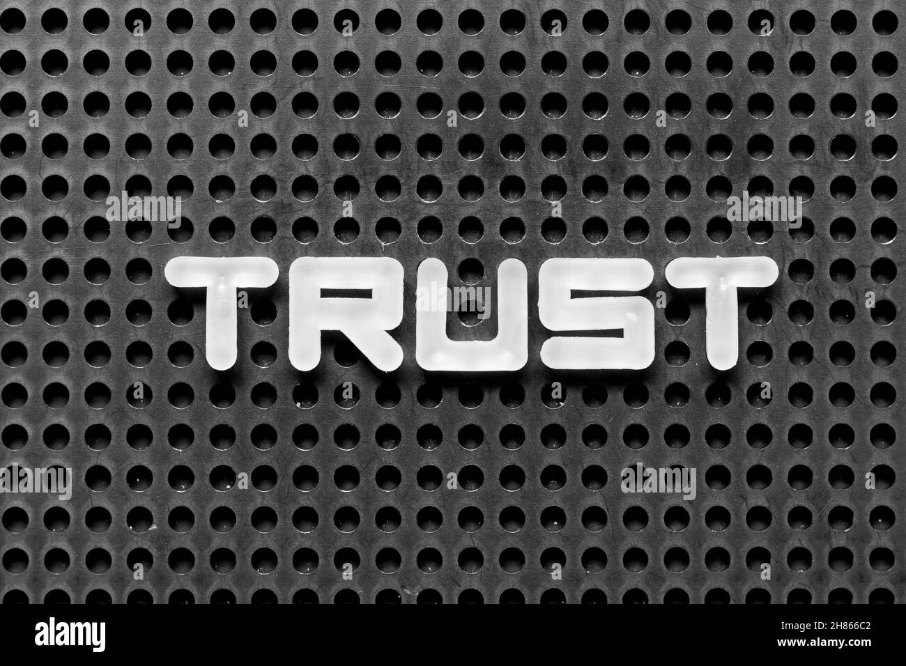 White alphabet letter in word trust on black pegboard background Stock ...
