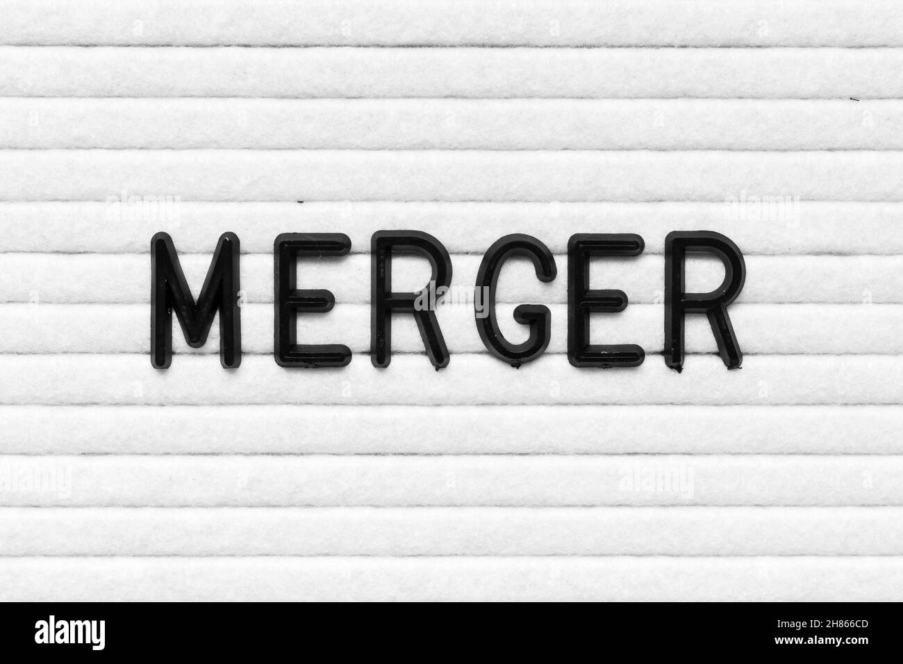 Black alphabet letter in word merger on white felt board background ...