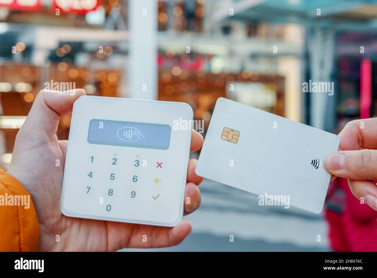 Crop unrecognizable client with plastic card making NFC payment on POS ...