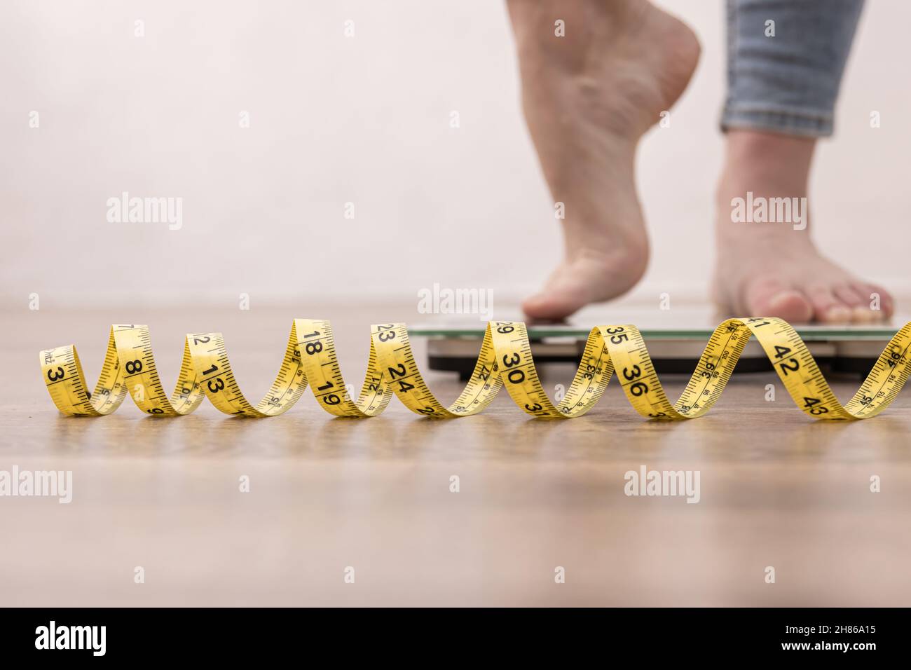 Female leg stepping on weigh scales with measuring tape Stock Photo - Alamy