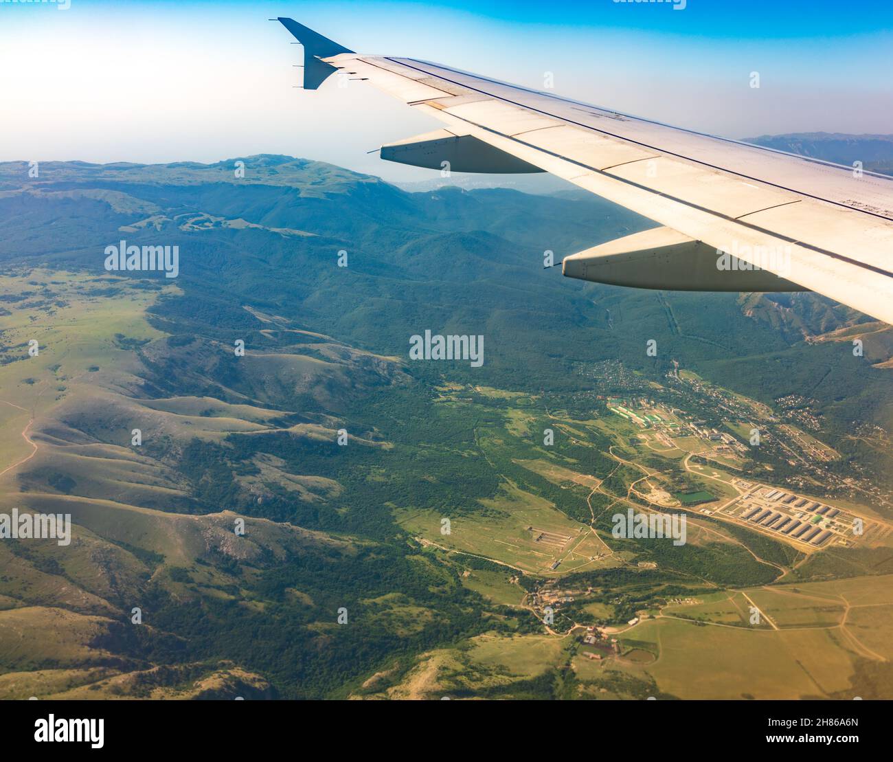 View of airplane wing, blue skies and green land during landing ...