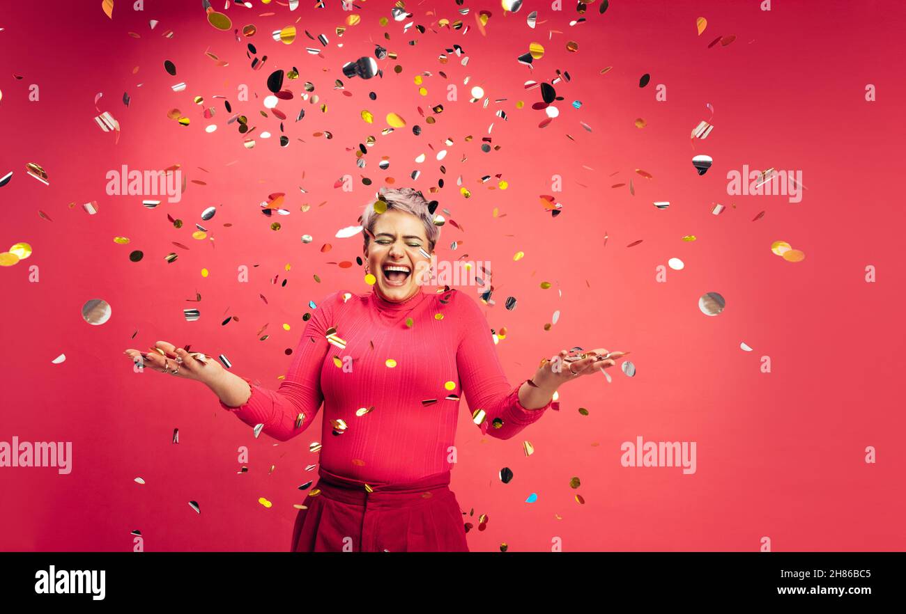 Celebrating with confetti. Carefree young woman getting excited while ...