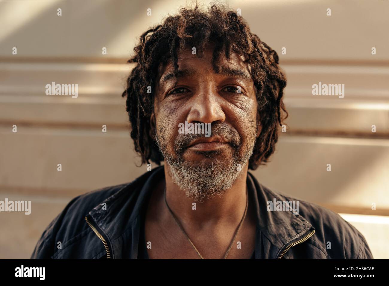 Closeup of a middle aged homeless man looking at the camera while ...
