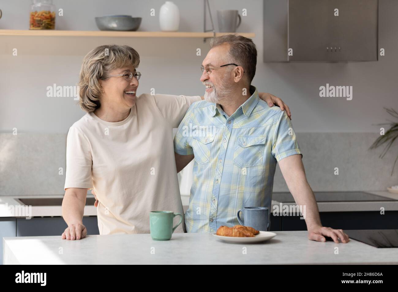 Cheerful mature married couple embracing in kitchen Stock Photo - Alamy