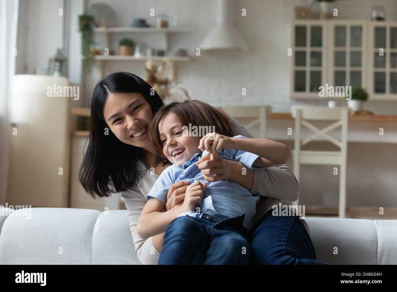 Cheerful Asian babysitter tickling little cute boy Stock Photo - Alamy
