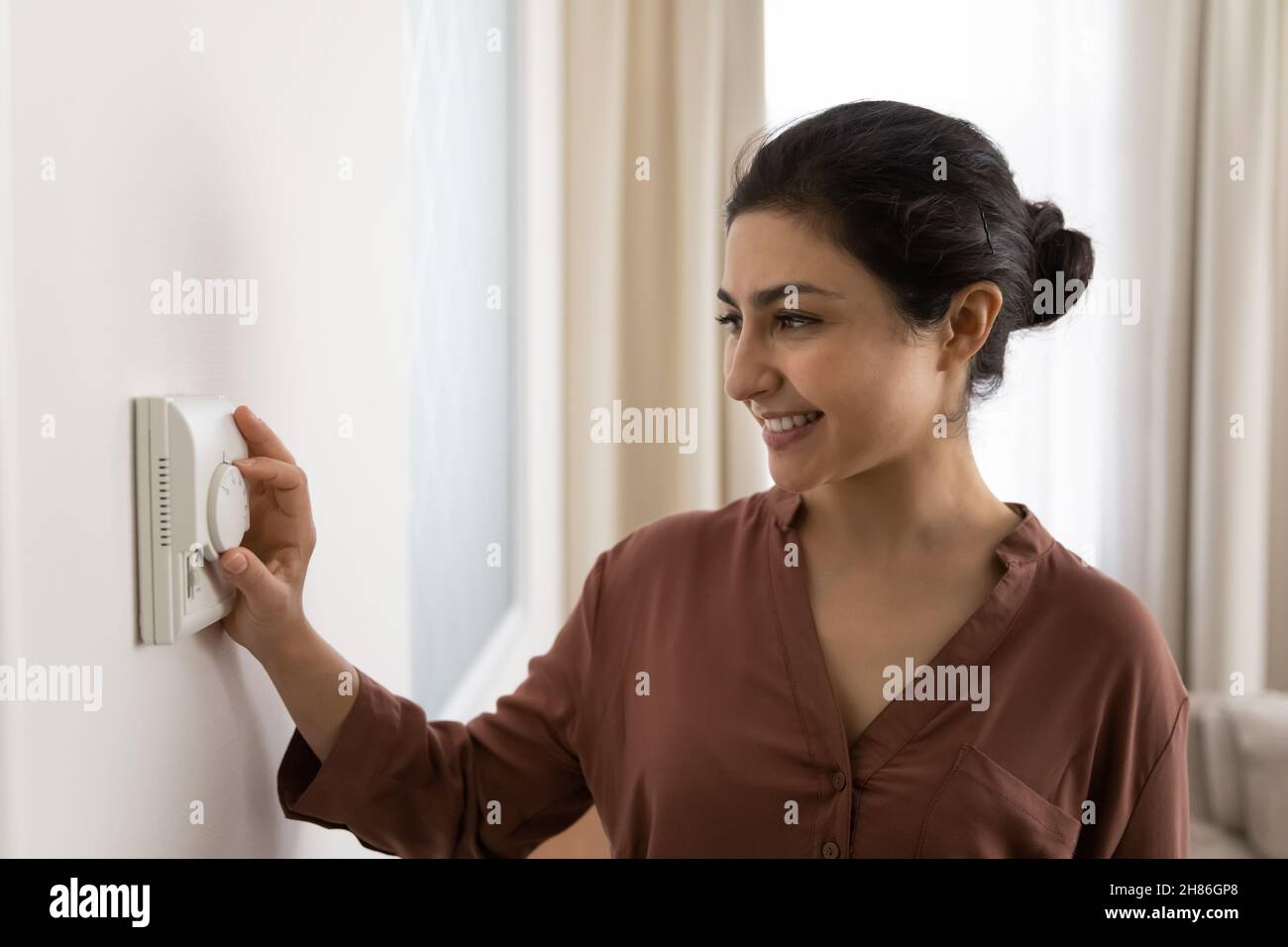 Happy young indian woman setting comfortable temperature Stock Photo ...