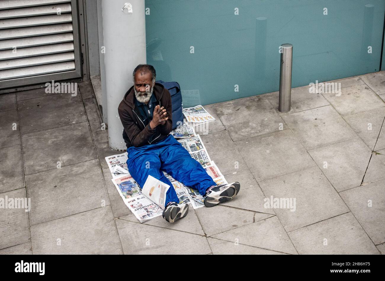 Homeless man, begging, sitting on newspapers in office doorway, london ...