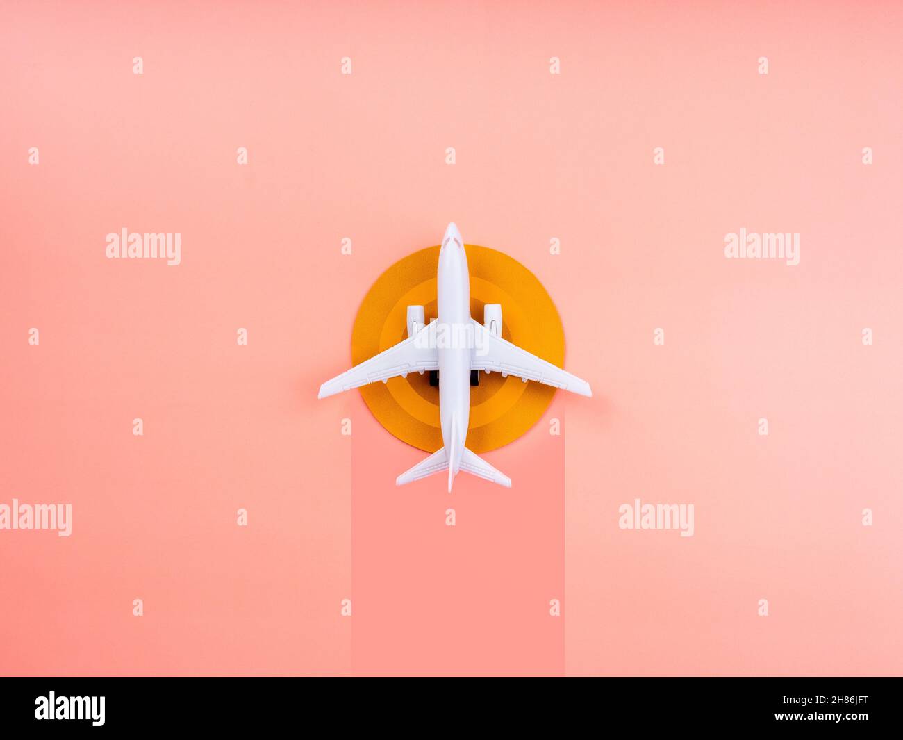 Plane model on yellow round target symbol on pastel pink color ...