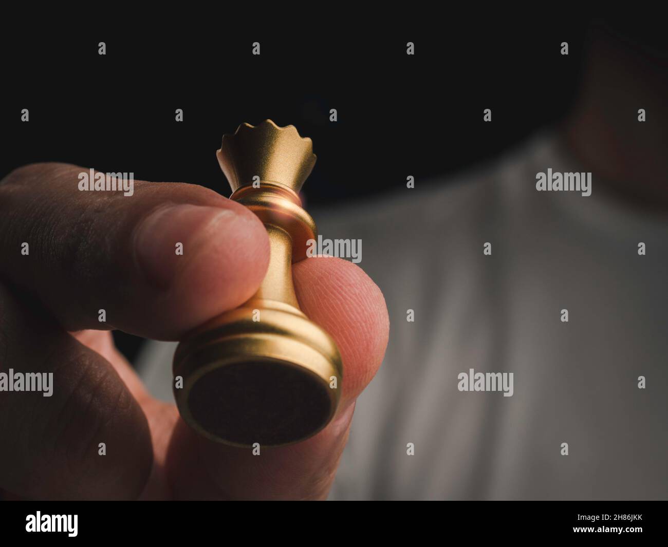 Close up gold queen chess piece in human hand in the air on dark ...