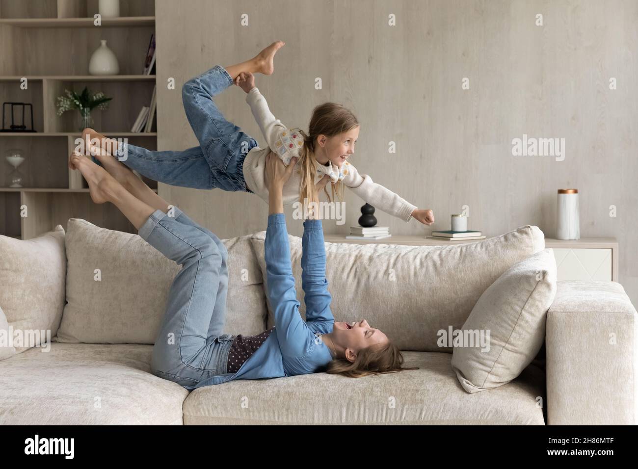 Flexible Happy Girl Making Acrobatic Moves In Hands Of Mother Stock