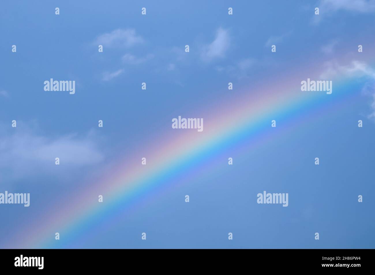 Rainbow on blue sky background Stock Photo - Alamy