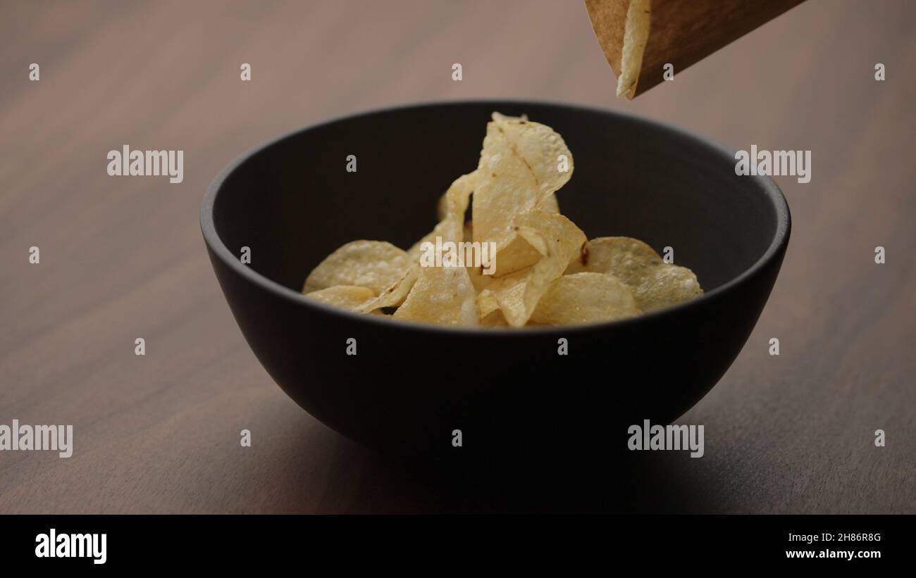 potato chips in black bowl on wood table, wide photo Stock Photo - Alamy