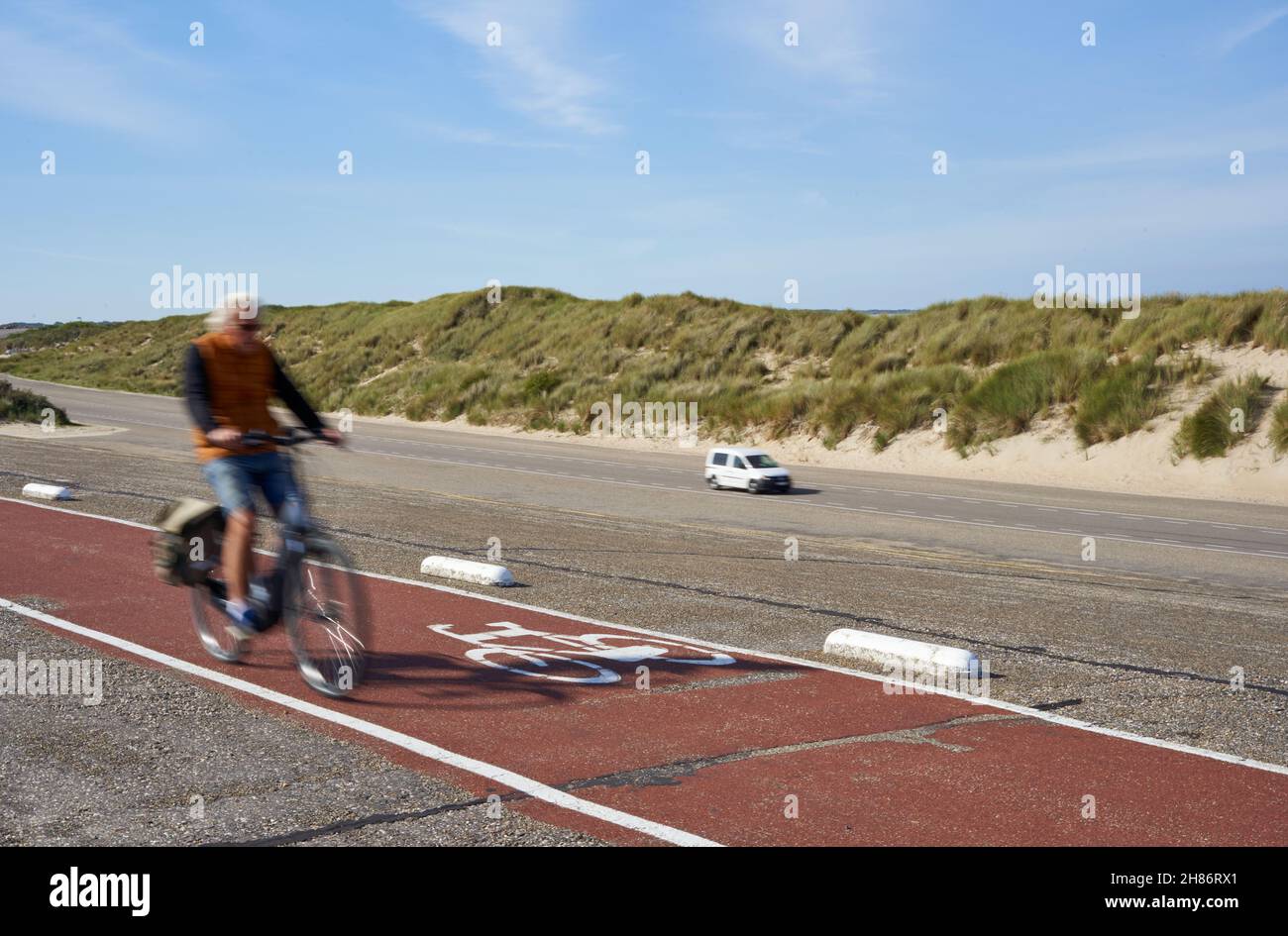 Red bike path in the Netherlands. Route on a dam in front of the grass ...