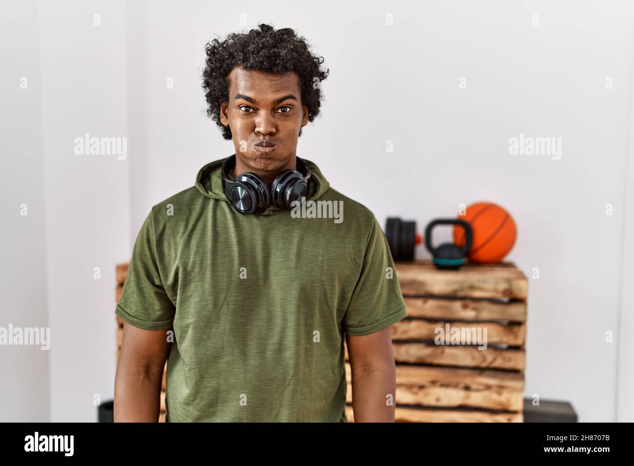 African man with curly hair wearing sportswear at the gym puffing ...