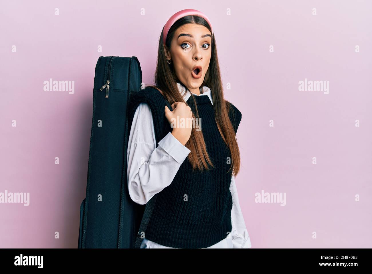 Beautiful brunette young musician woman wearing guitar case scared and ...