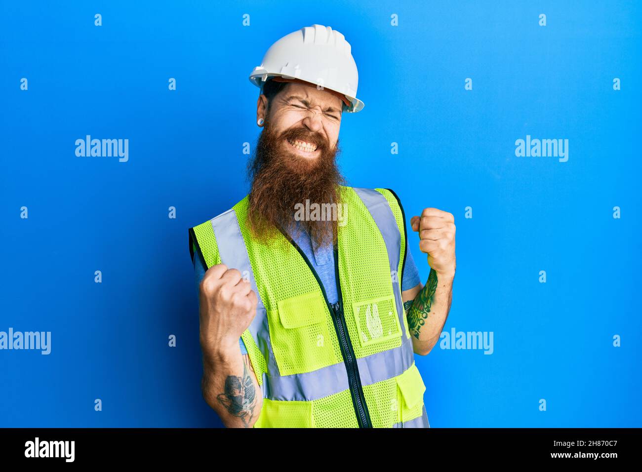 Redhead man with long beard wearing safety helmet and reflective jacket ...
